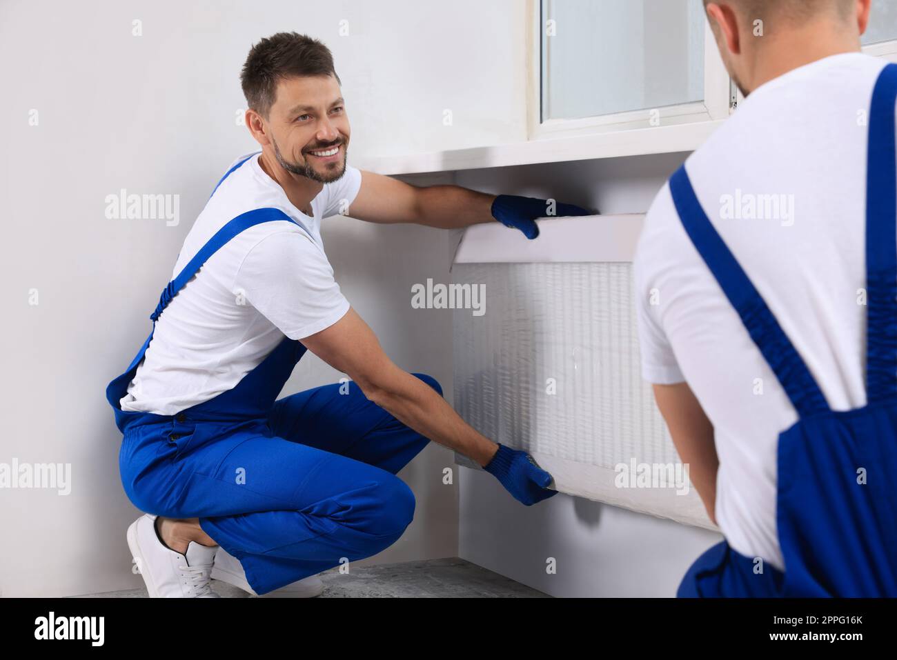 Professional plumbers installing new heating radiator in room Stock ...