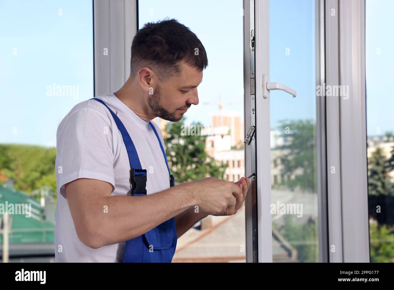 Worker adjusting installed window with screwdriver indoors Stock Photo ...