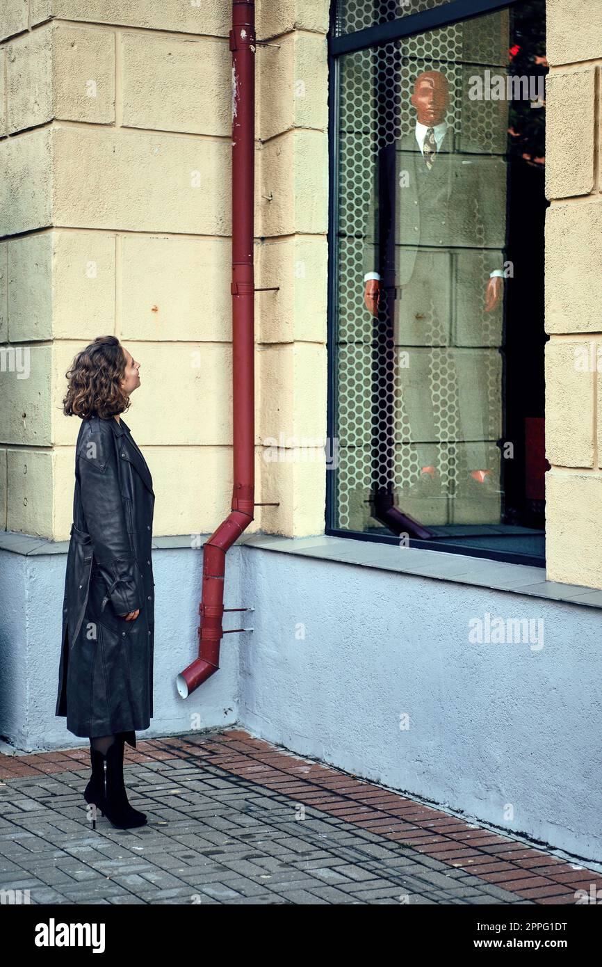 Lady looking at the shop window at man's suit standing on the street ...