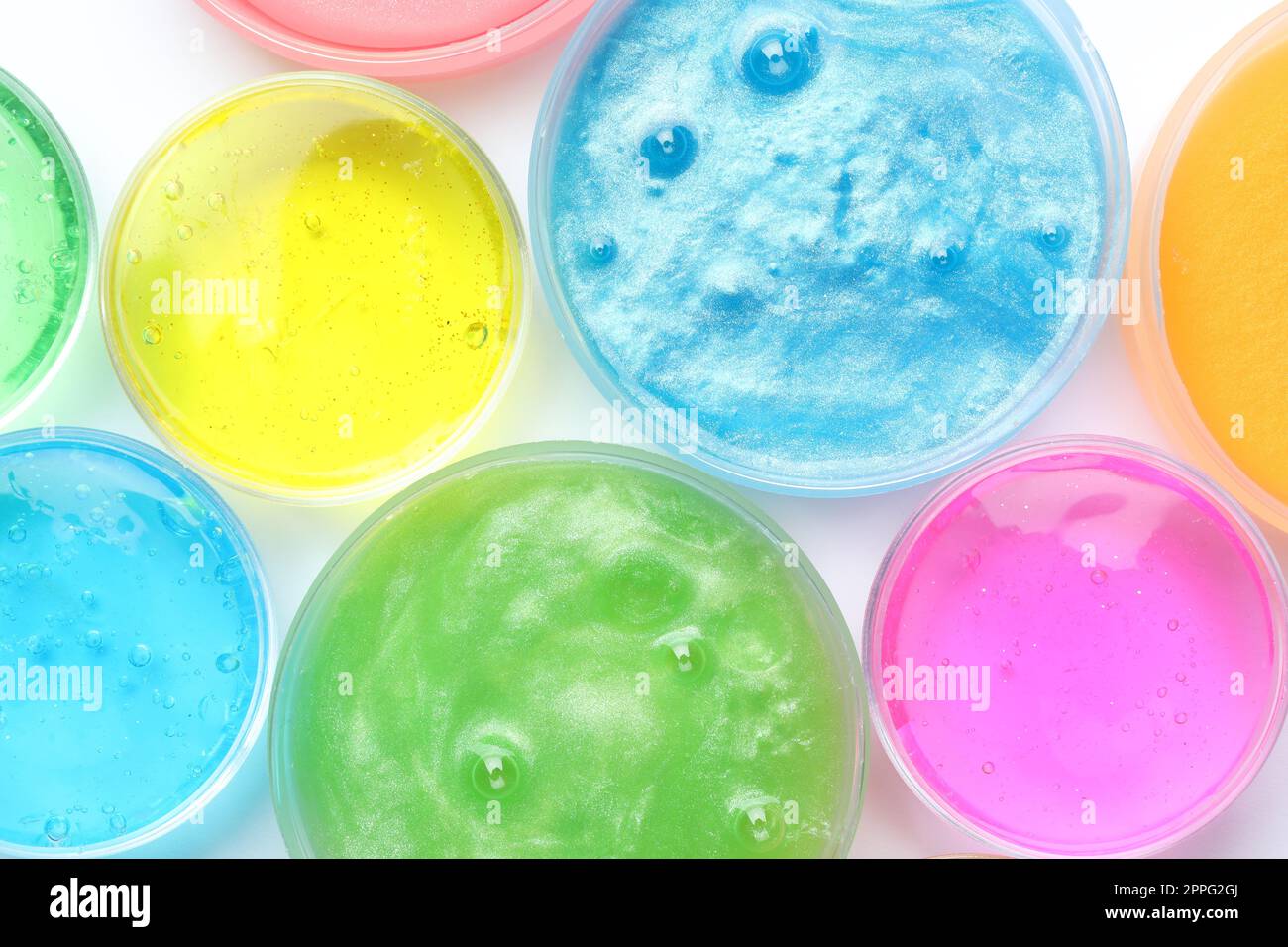Colorful slimes in plastic containers on white background, top view ...