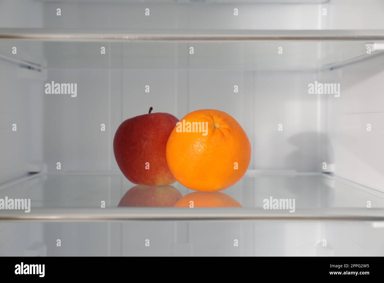 Apple and orange on shelf inside modern refrigerator Stock Photo - Alamy