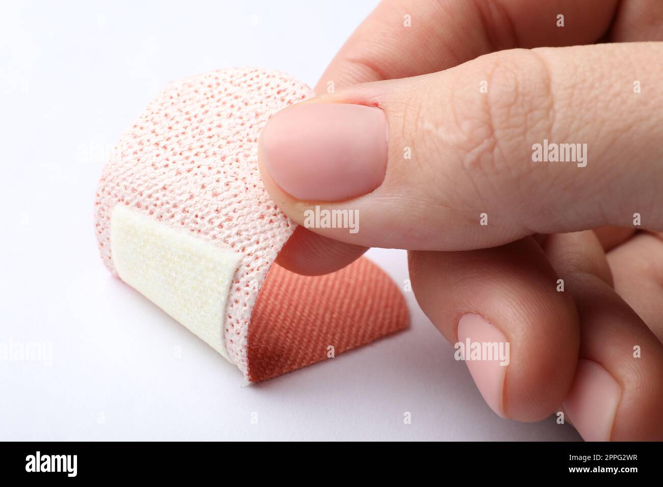 Woman putting sticking plaster on white background, closeup. First aid ...