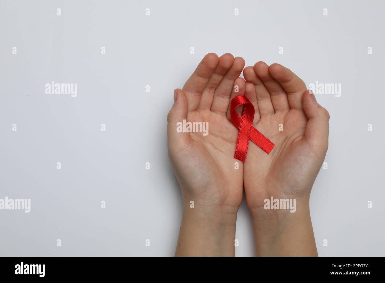 Little girl holding red ribbon on white background, top view. AIDS ...