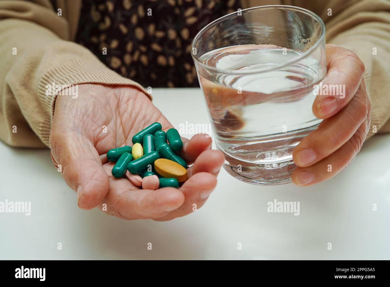 Asian elderly woman holding pill drug with water in glass, strong ...