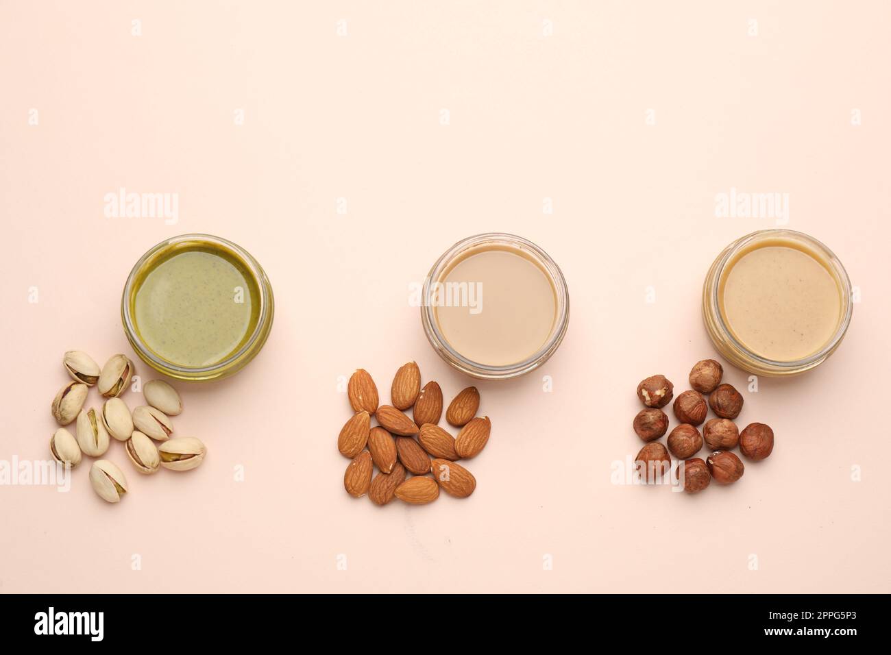 Different types of delicious nut butters and ingredients on beige ...