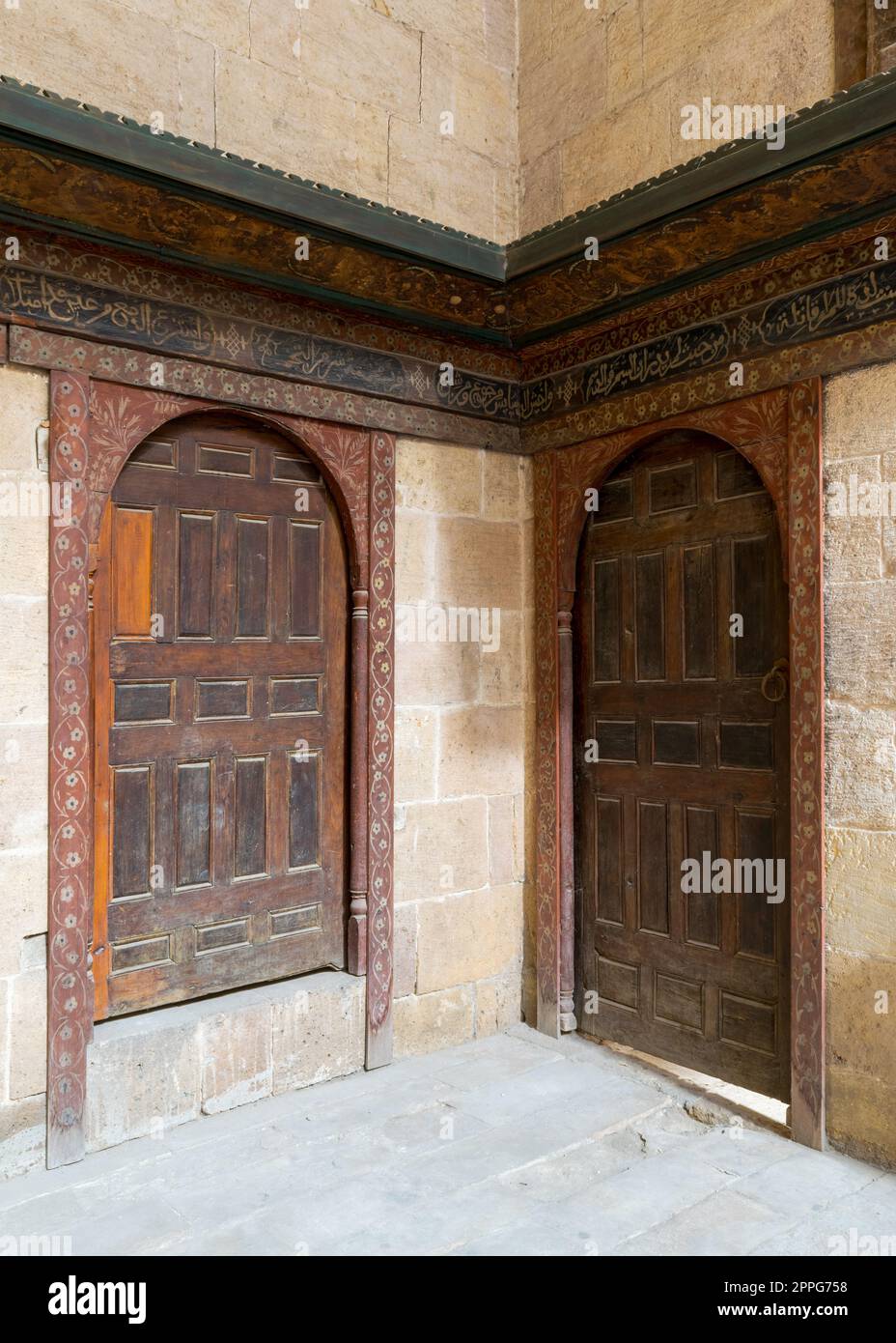 Two wooden aged ornate vaulted perpendicular doors on stone bricks ...