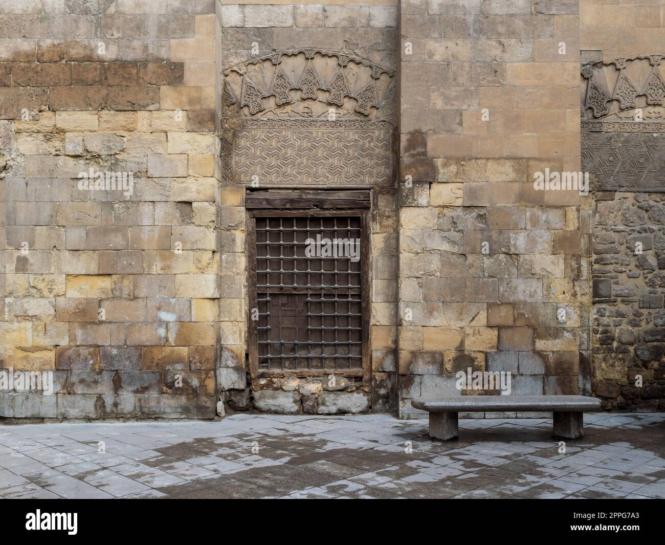 Wooden window with decorated iron grid over stone bricks wall and ...