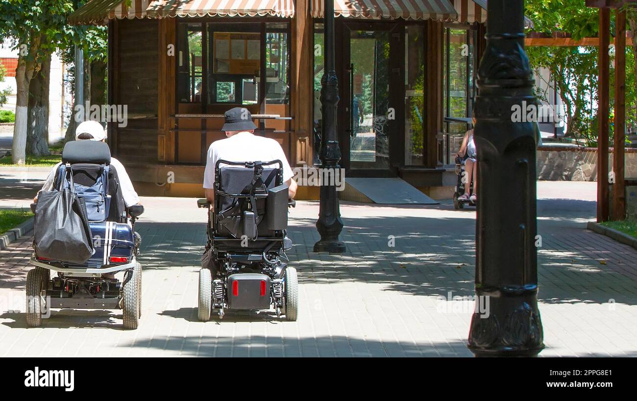 Two disabled person on an electric wheelchair on a city street Stock ...