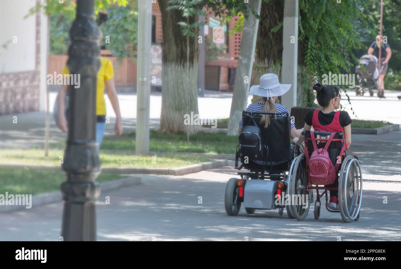 Two disabled person on an electric wheelchair on a city street Stock ...