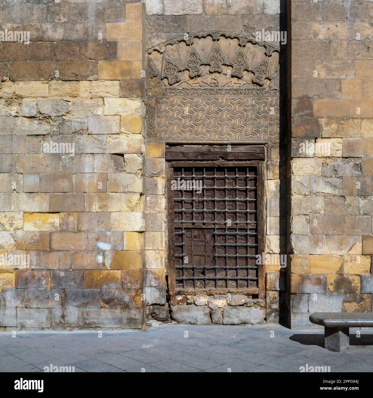 Grunge wooden window with decorated iron grid over stone bricks wall ...