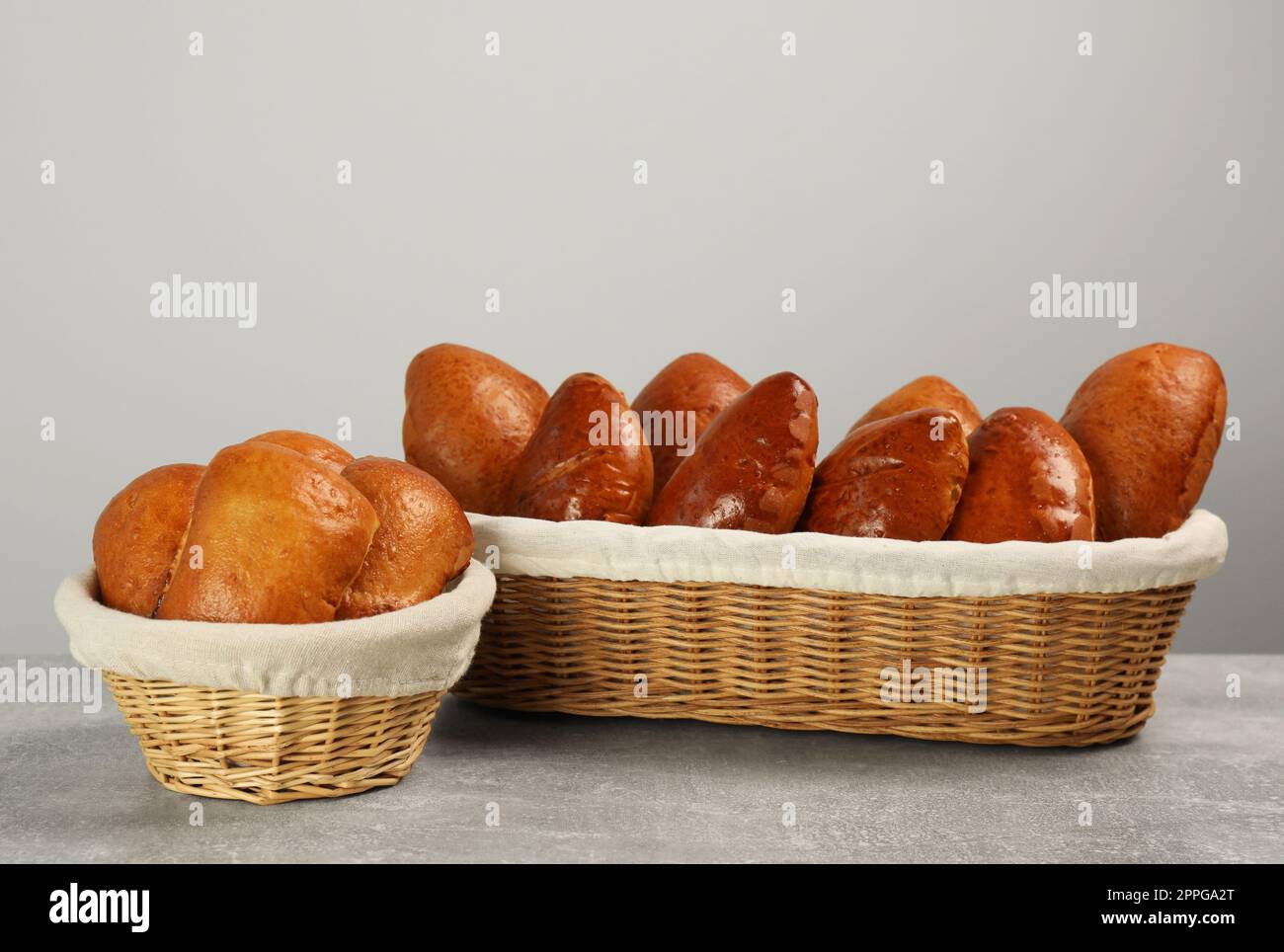 Delicious baked patties in wicker baskets on light grey table Stock ...