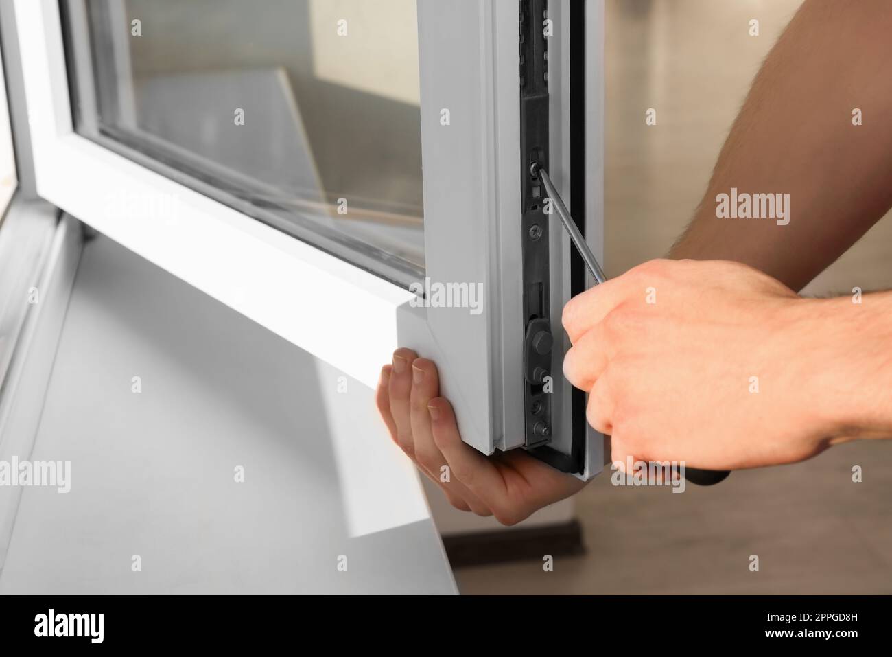 Worker adjusting installed window with screwdriver indoors, closeup ...