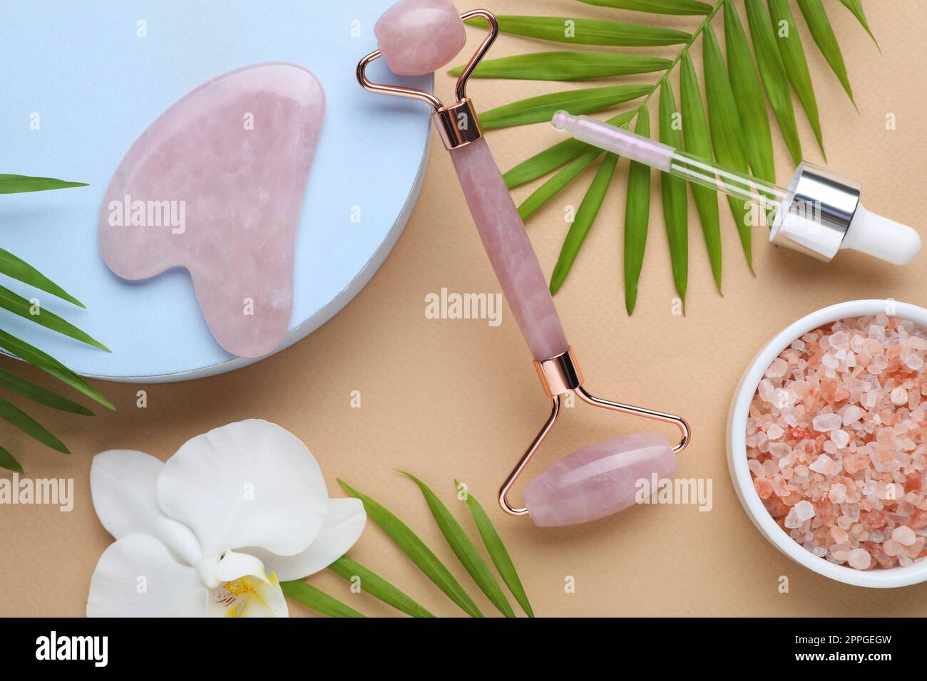 Flat lay composition with gua sha stone and face roller on beige ...