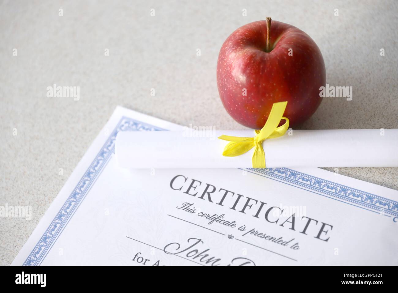 A certificate of achievement lies on table with small scroll and red ...