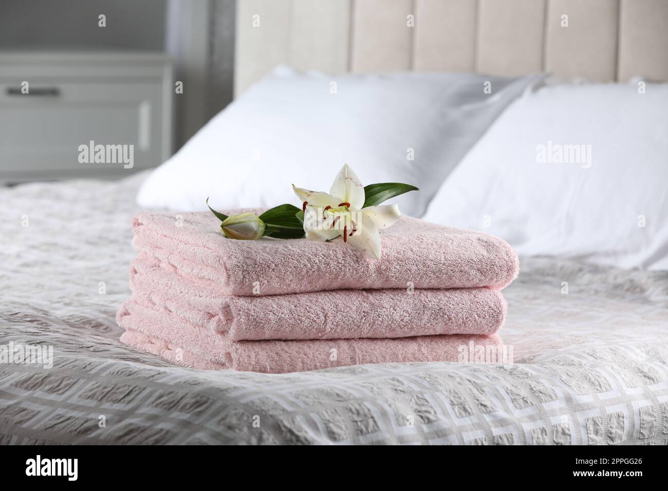 Stack of clean towels and lily flowers on bed indoors Stock Photo - Alamy