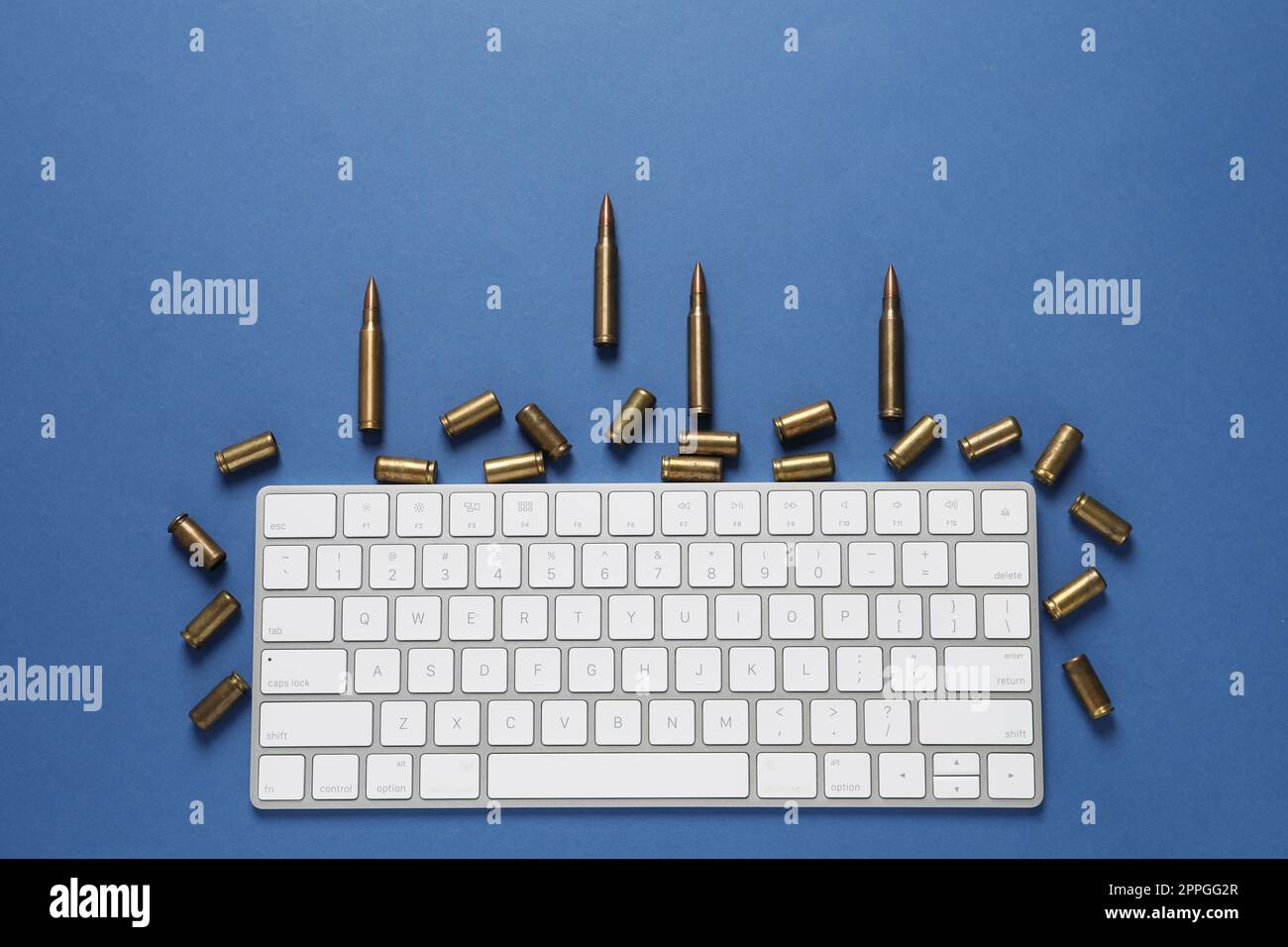 Bullets and computer keyboard on blue background, flat lay. Hybrid ...