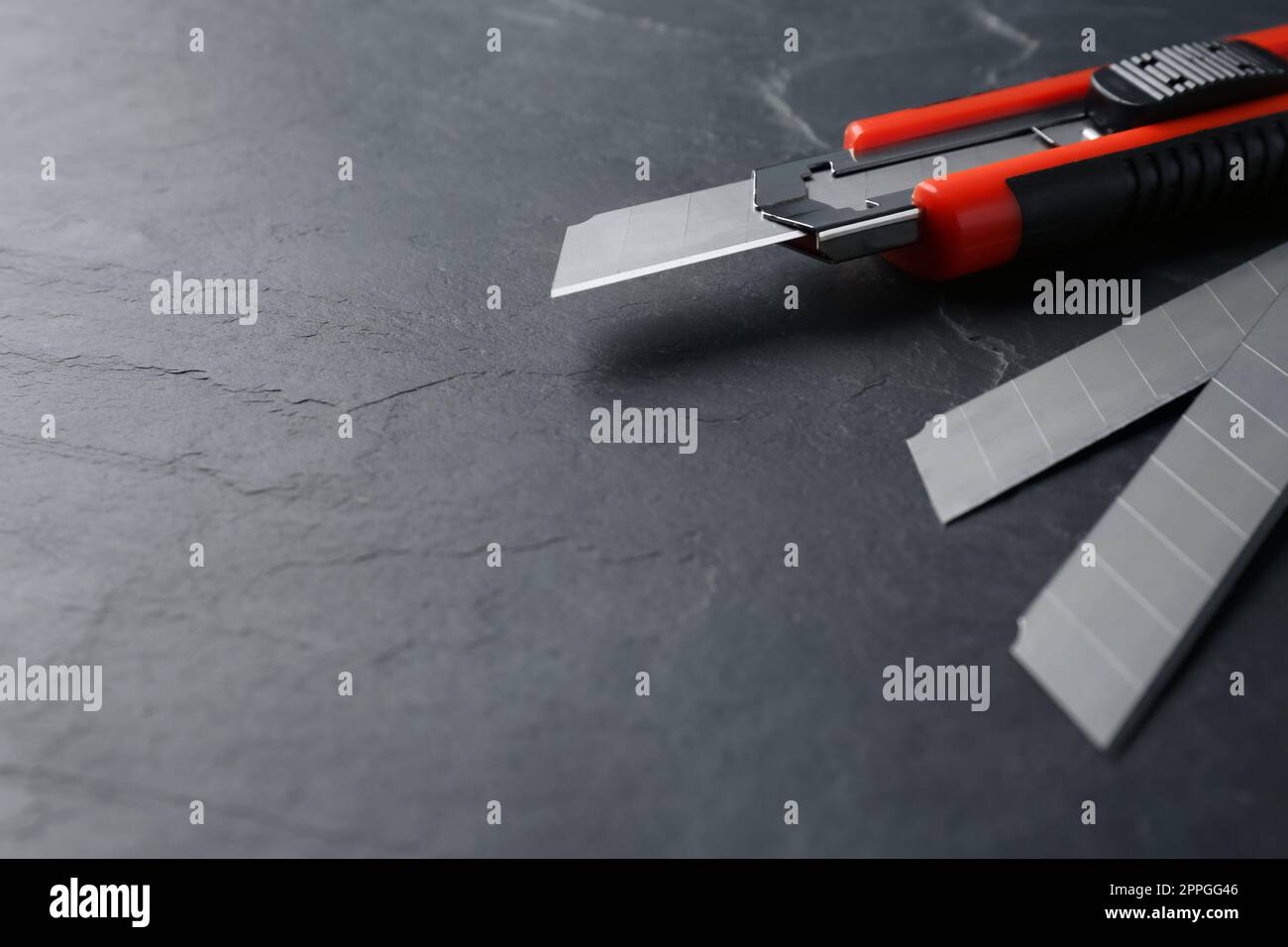 Utility knife and blades on black table. Space for text Stock Photo - Alamy