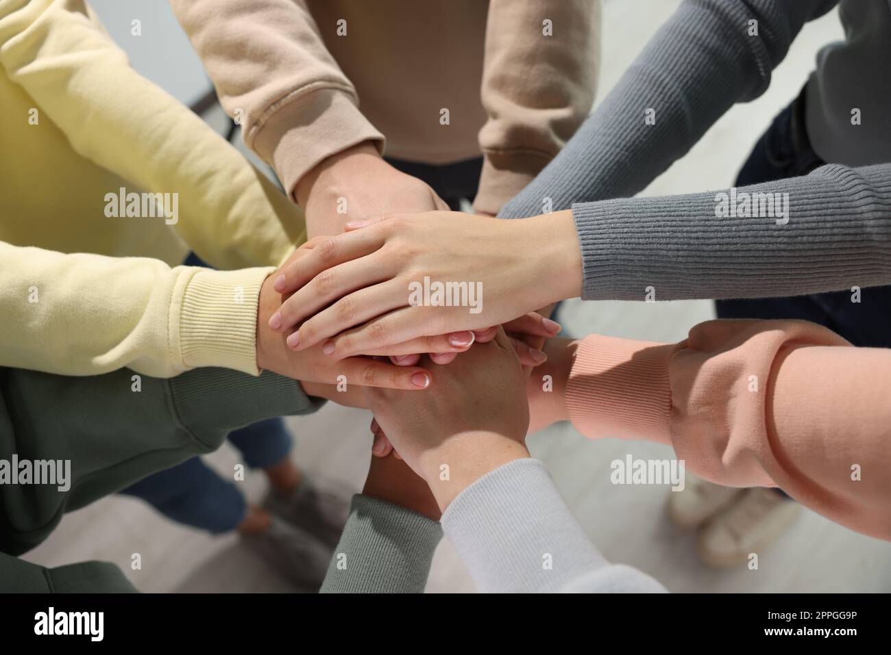 Group of people holding hands together indoors, above view. Unity ...