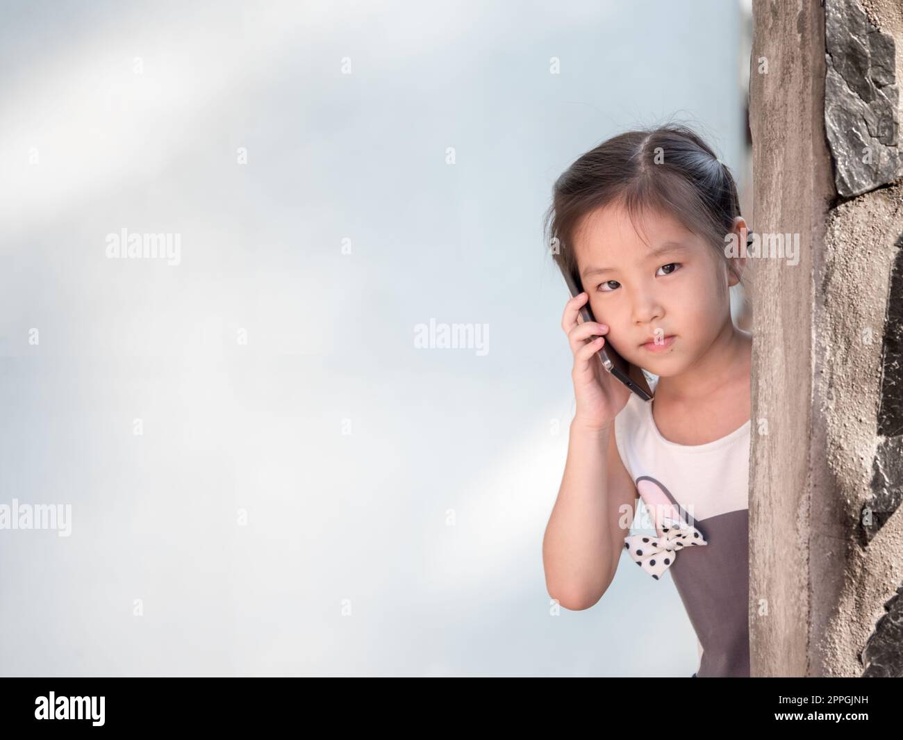 Asian girl hiding behind the wall, use the smart phone Stock Photo - Alamy