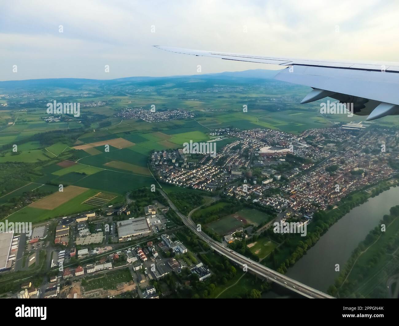 Airplane window view of wing, highway junctions and green forest at ...