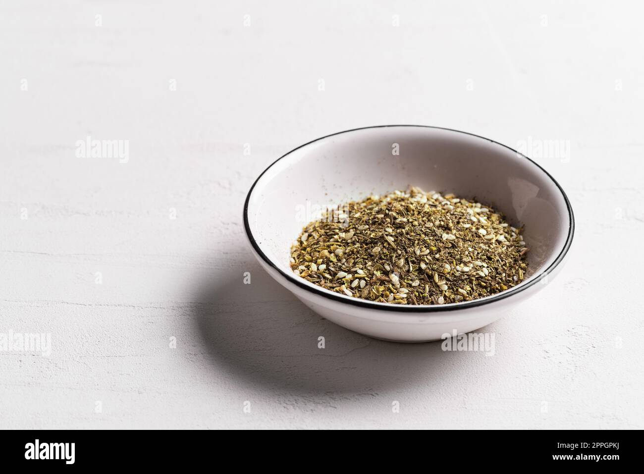 Mixed zaatar or zatar spices in white bowl on white background, copy ...