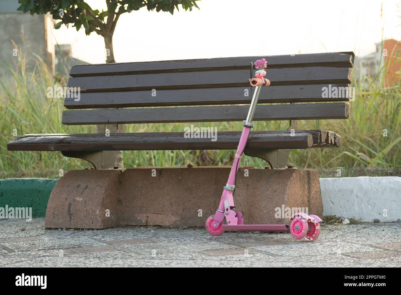 Children scooter beside a park bench Stock Photo - Alamy