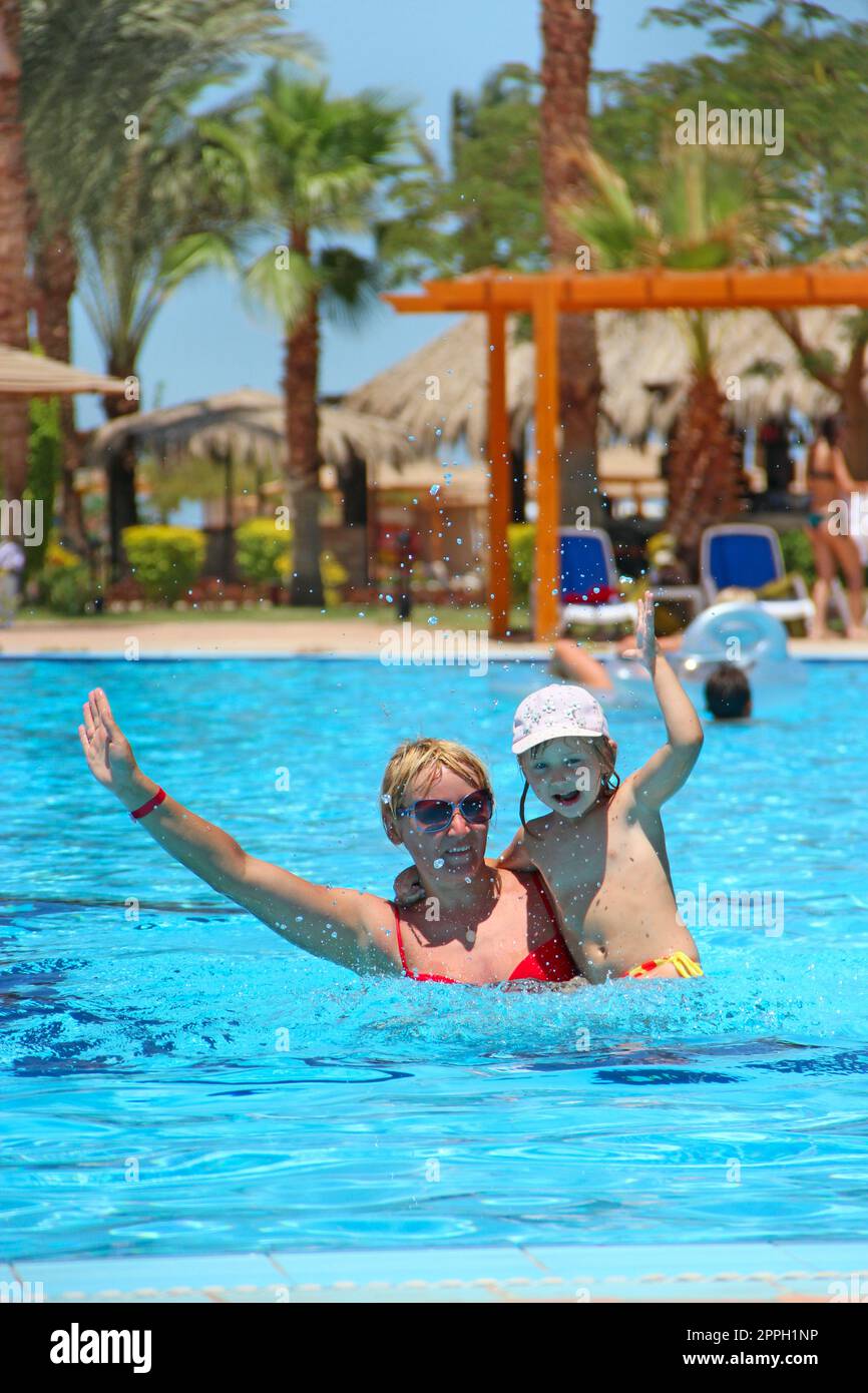 Happy Mother Having Fun Jumping With Her Daughters In Swimming Pool