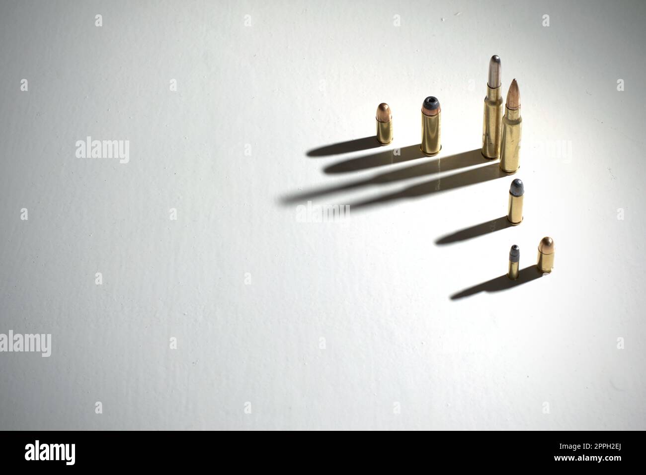 Bullets of different calibers standing on a white surface with dark ...