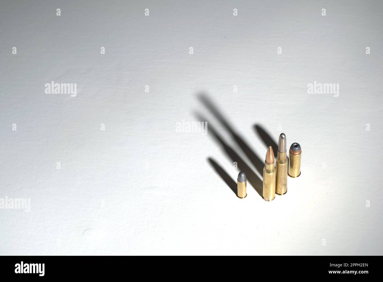 Bullets of different calibers standing on a white surface with dark ...