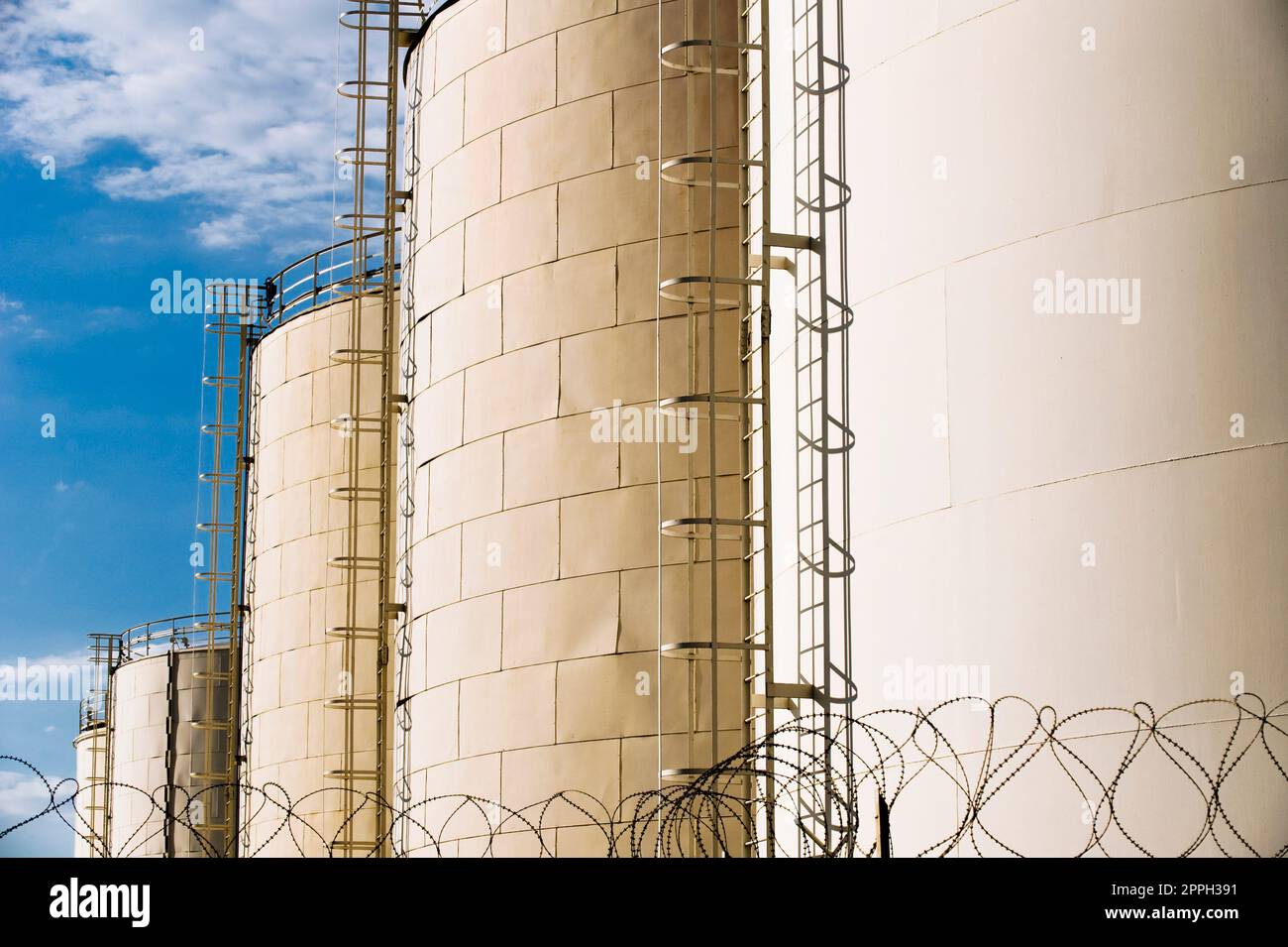 Fuel tanks in a compound secured with barbed wire Stock Photo - Alamy