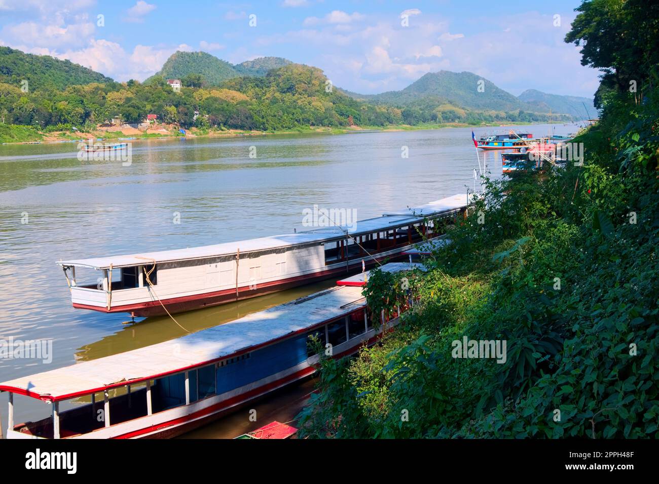 Long boats and barges sailing on the Mekong River near Luang Prabang ...