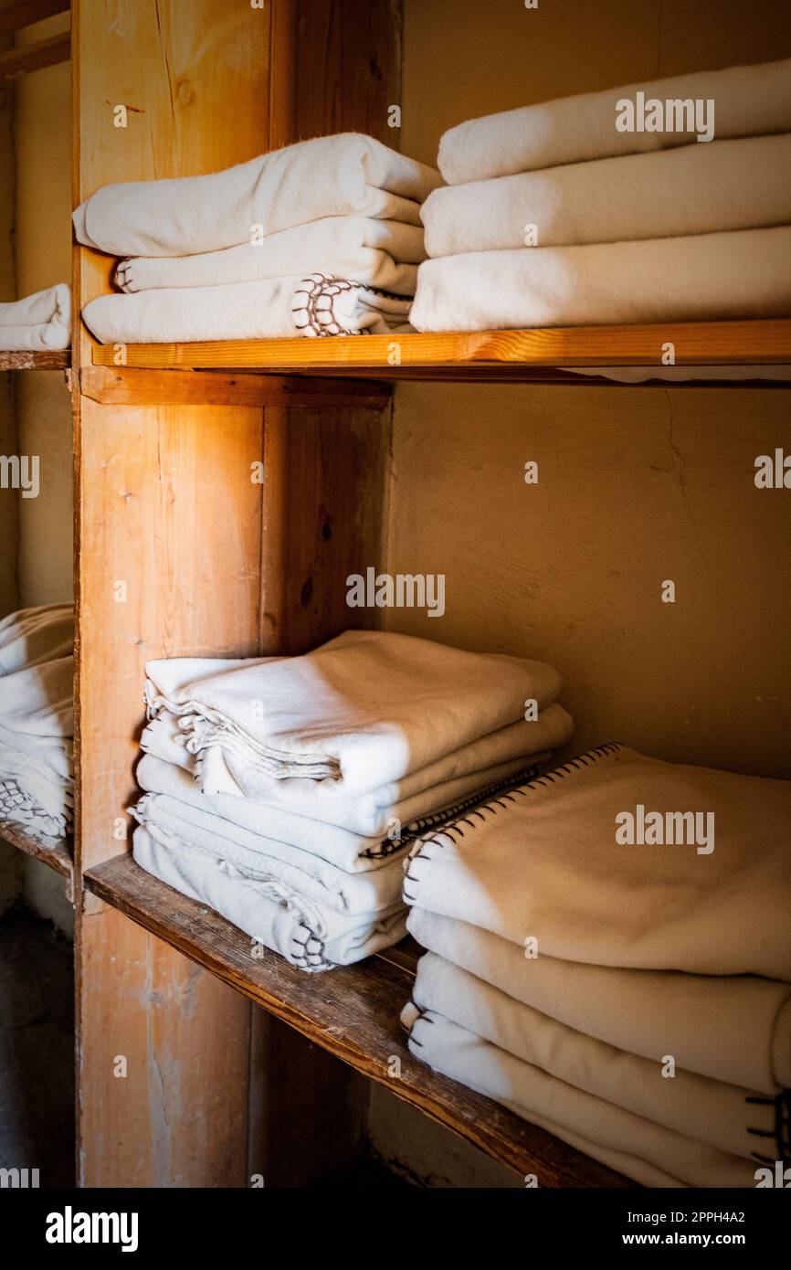 Neatly folded white 1950s style blankets on shelves in a mental asylum ...