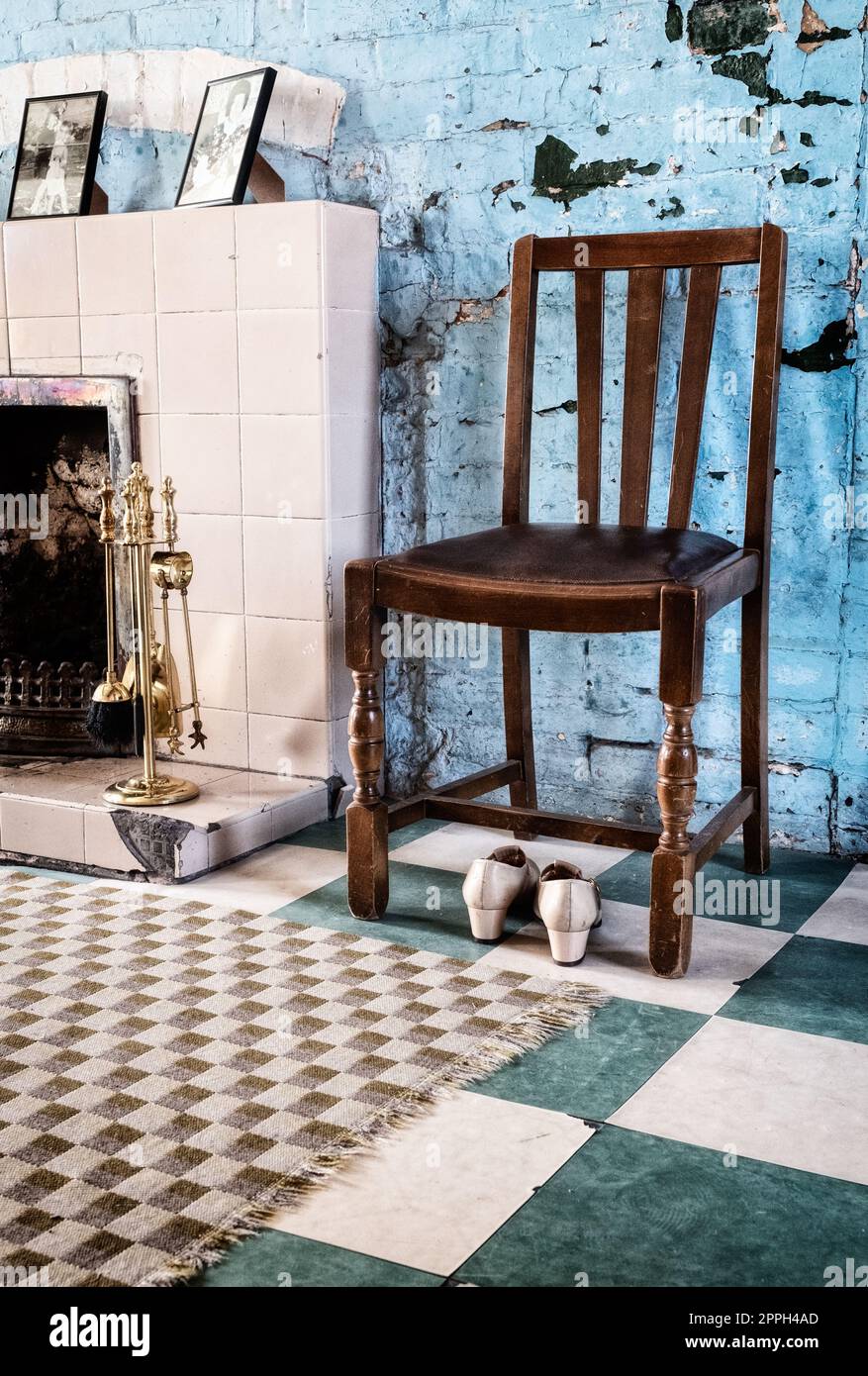 A pair of woman's shoes neatly placed under a wooden chair in a 1950's ...