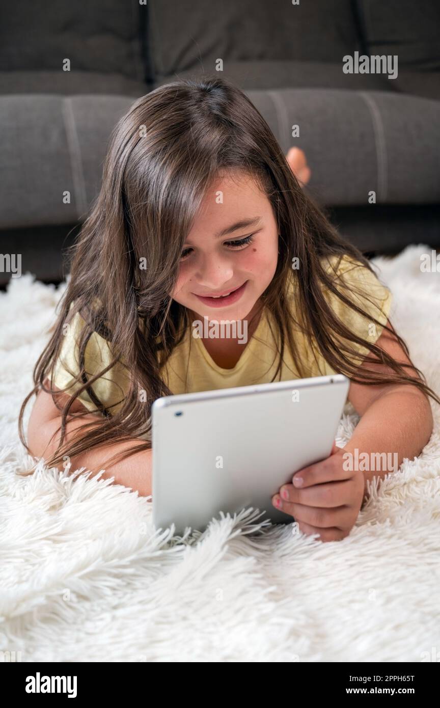 Adorable little girl using a digital tablet on the floor at home Stock ...