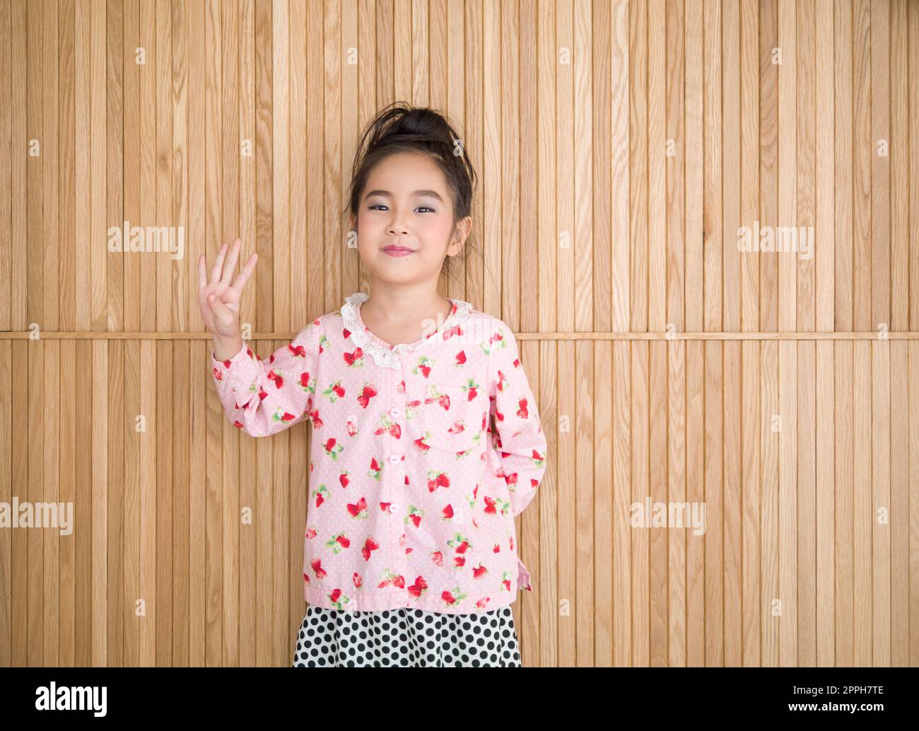 Portrait of happy little girl , wood background, show four fingers ...