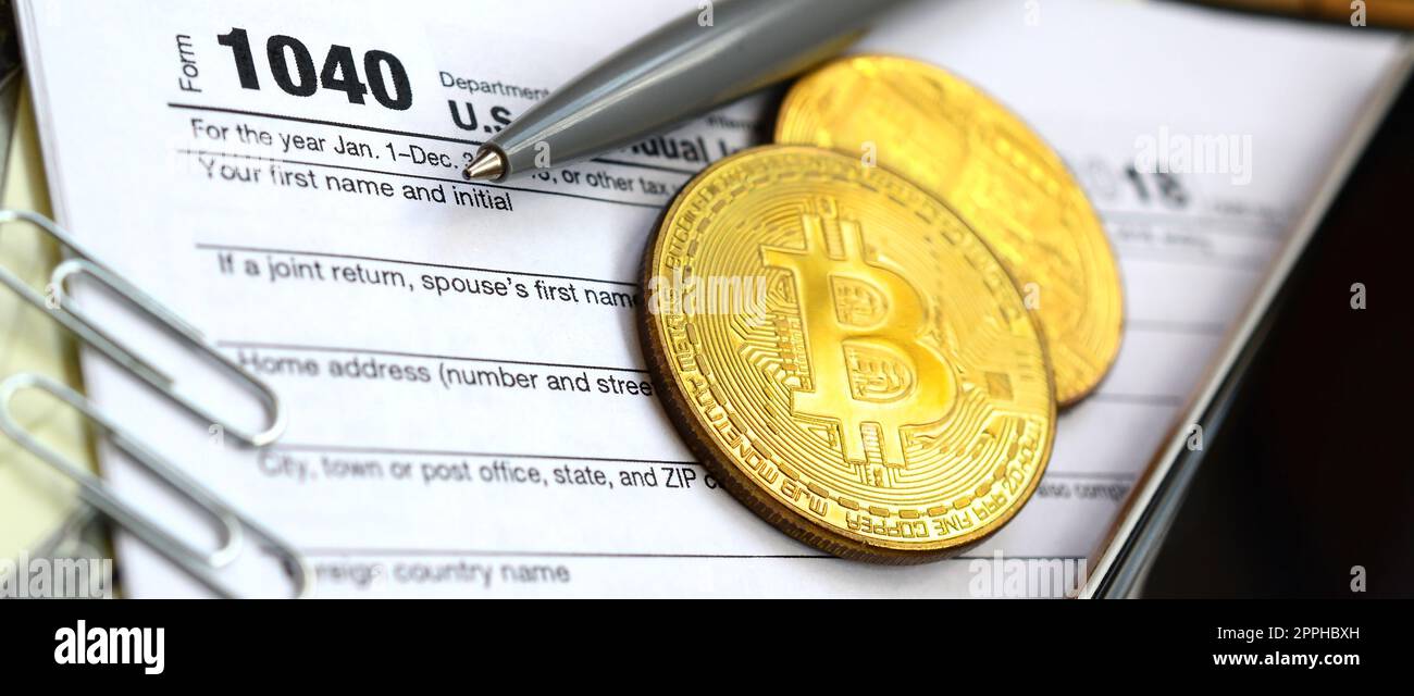 The pen, bitcoins and dollar bills is lies on the tax form 1040 U.S ...