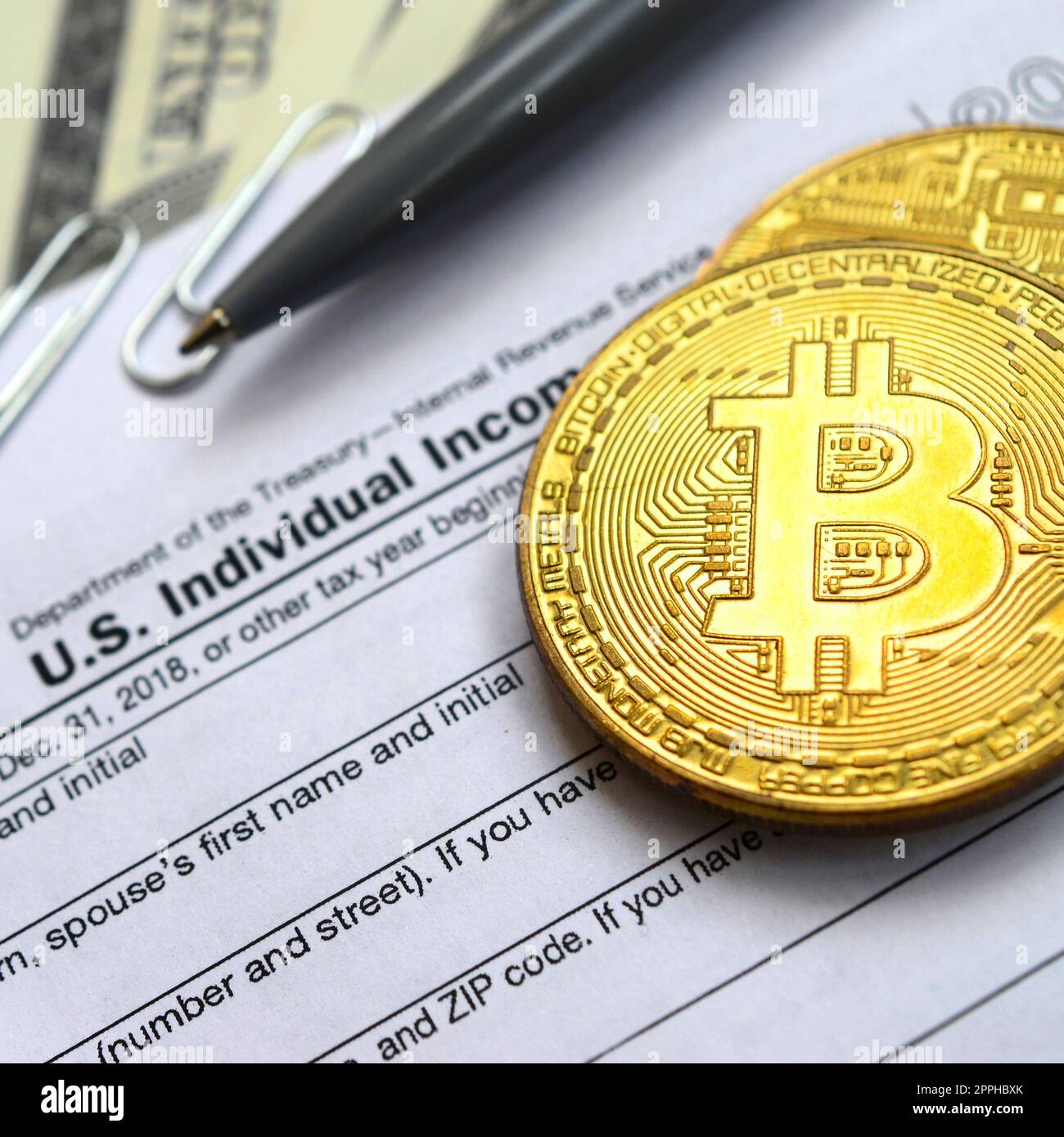 The pen, bitcoins and dollar bills is lies on the tax form 1040 U.S ...