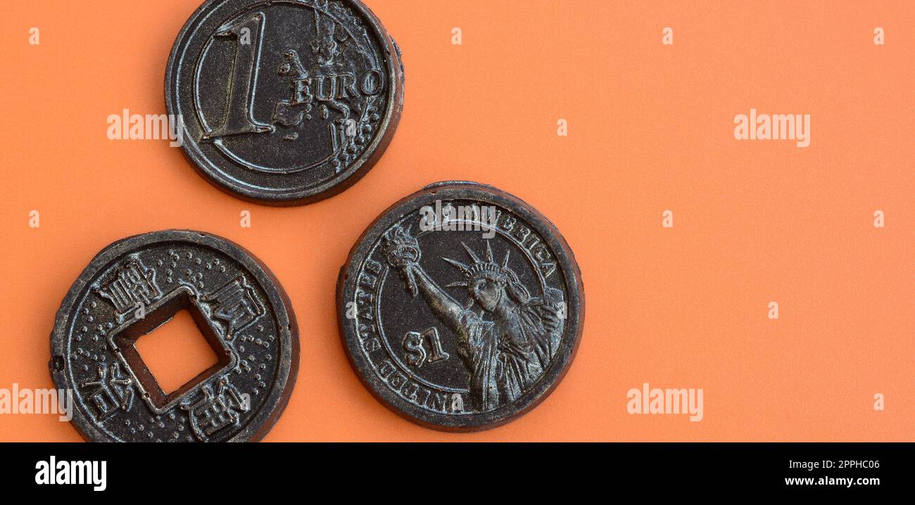 Three chocolate products in the form of Euro, USA and Japan coins lie ...