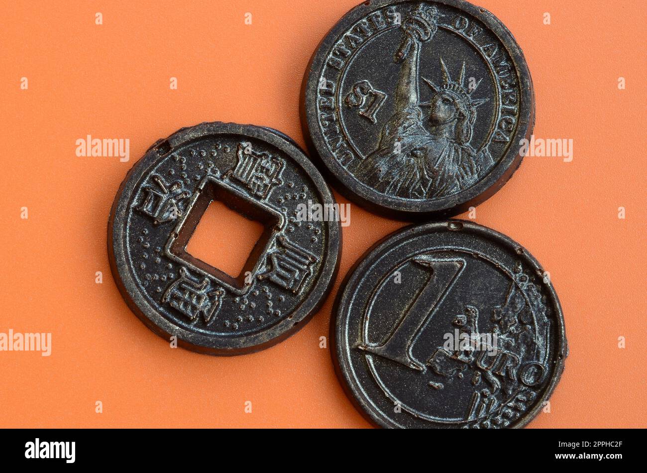 Three chocolate products in the form of Euro, USA and Japan coins lie ...
