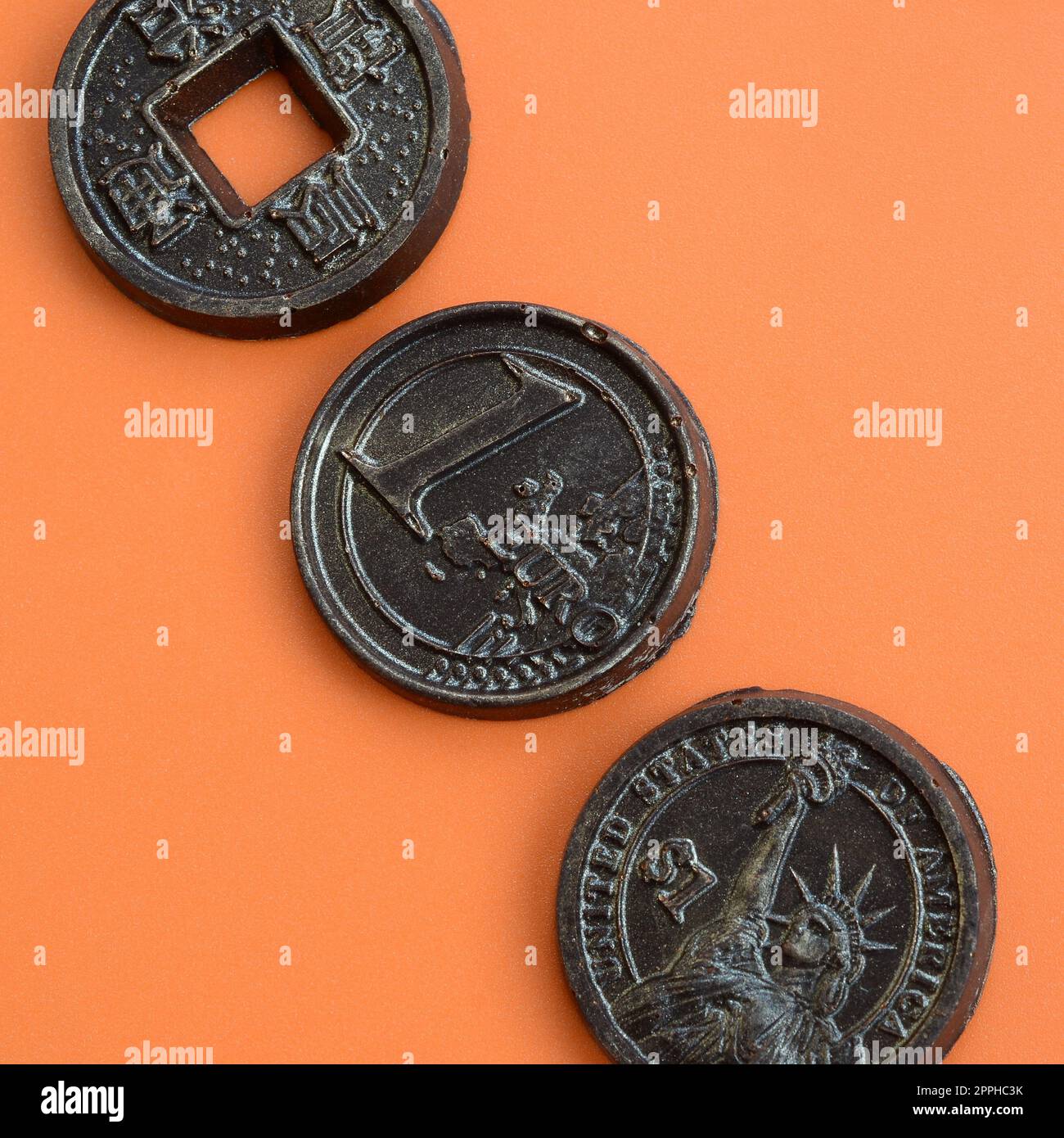 Three chocolate products in the form of Euro, USA and Japan coins lie ...