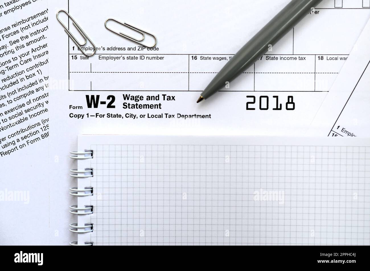 The pen and notebook on the tax form W-2 Wage and Tax Statement. The ...