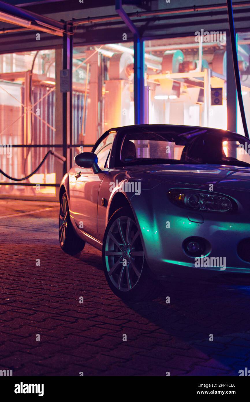 Silver JDM convertible at night in front of a car wash and neon lights ...