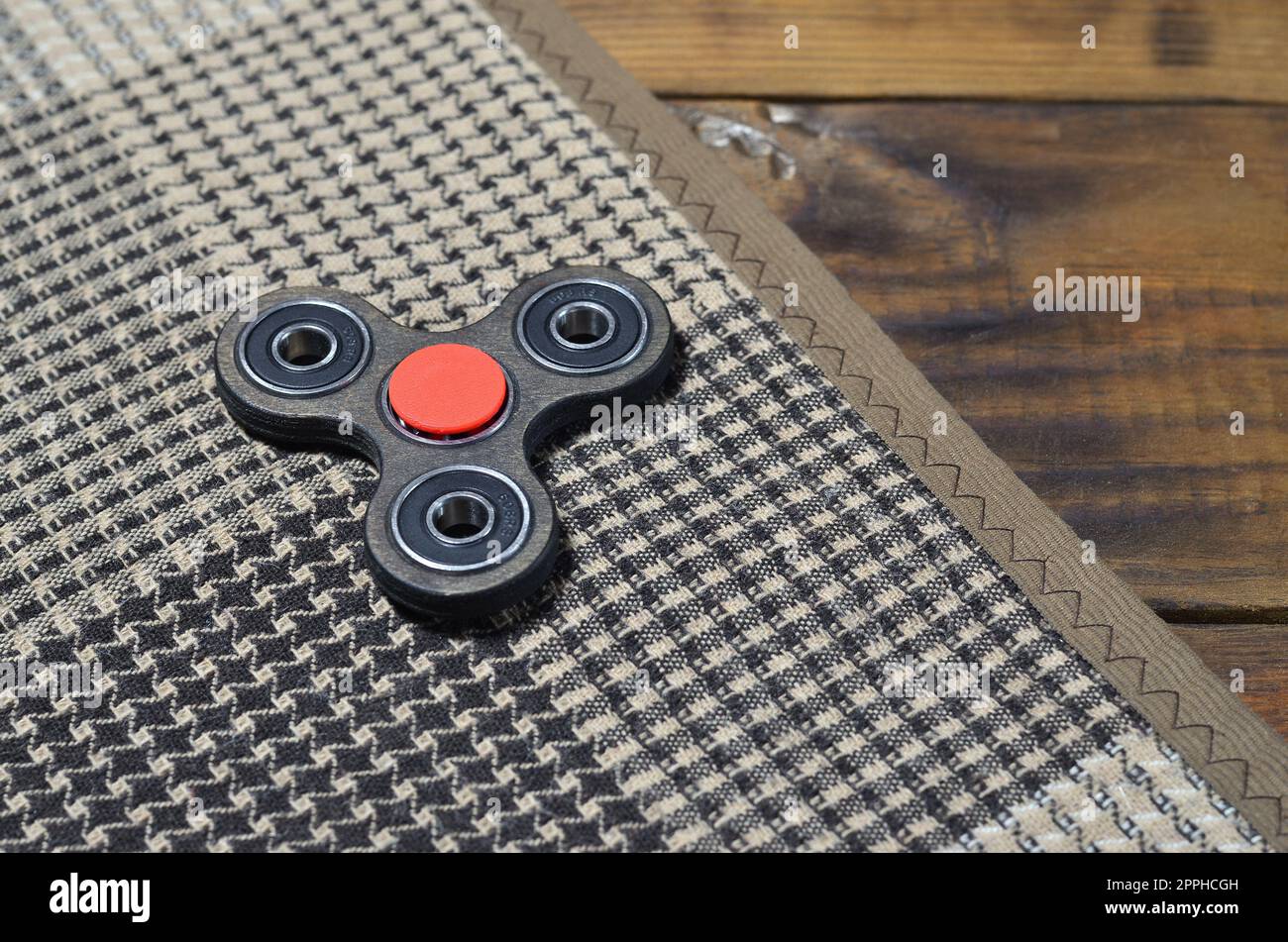 A rare wooden handmade spinner lies on a checkered plaid on a brown ...
