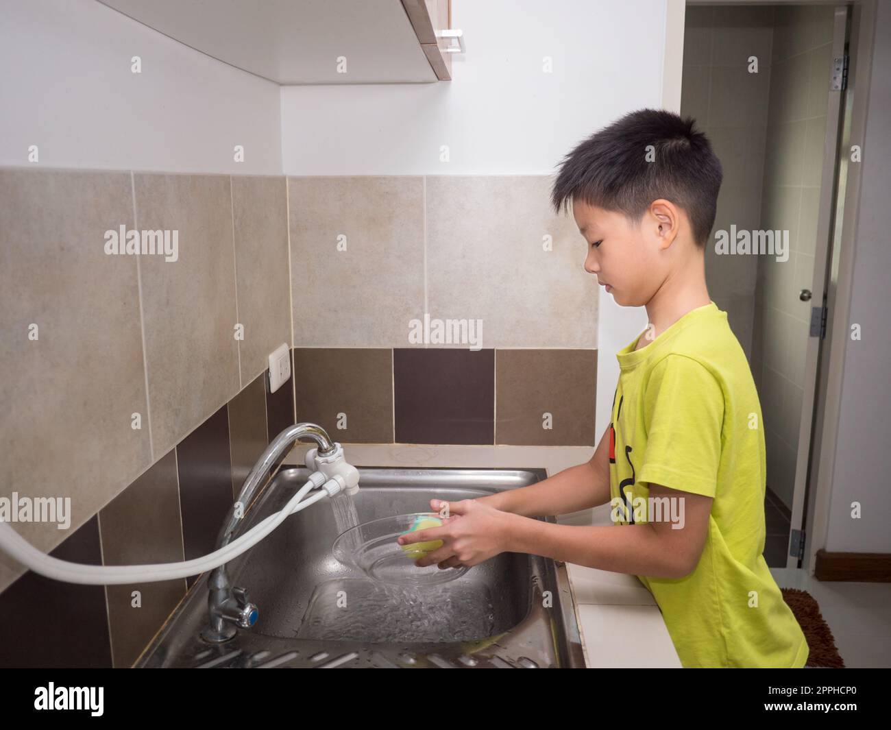 Adorable kid boy washing dishes in domestic kitchen. Child having fun ...