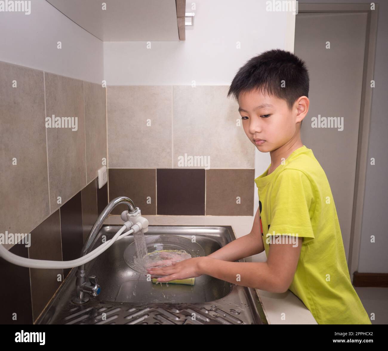 Adorable kid boy washing dishes in domestic kitchen. Child having fun ...