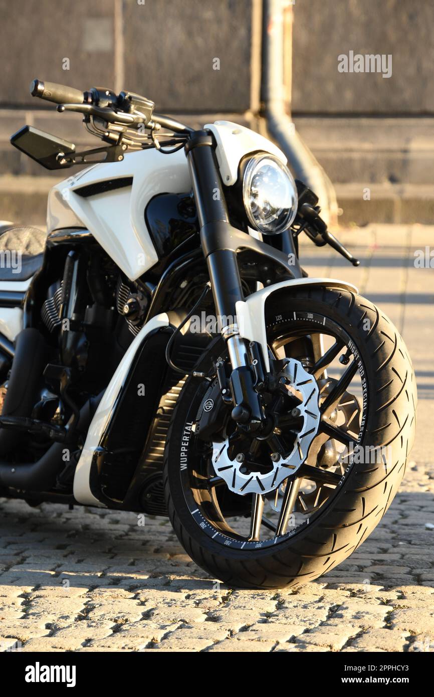 Vertical closeup of a white chopper motorcycle parked under the sunlight. Harley Davidon in ...