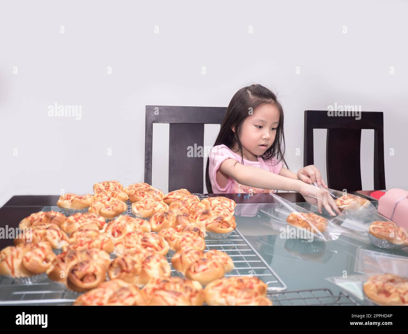 Adorable kid girl separate packing baked pork sausage with mayonnaise ...