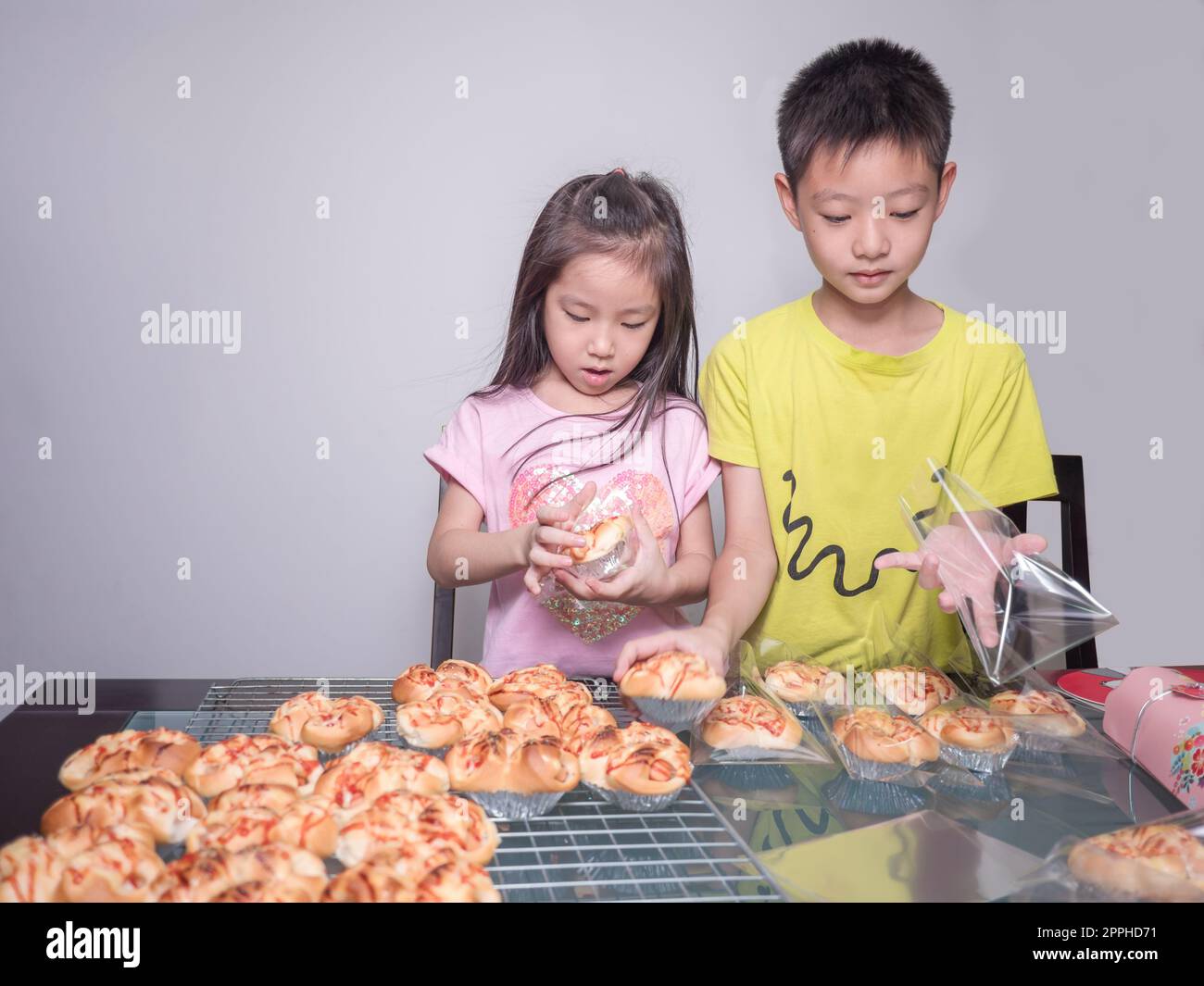 Adorable kid girl and boy separate packing baked pork sausage with ...