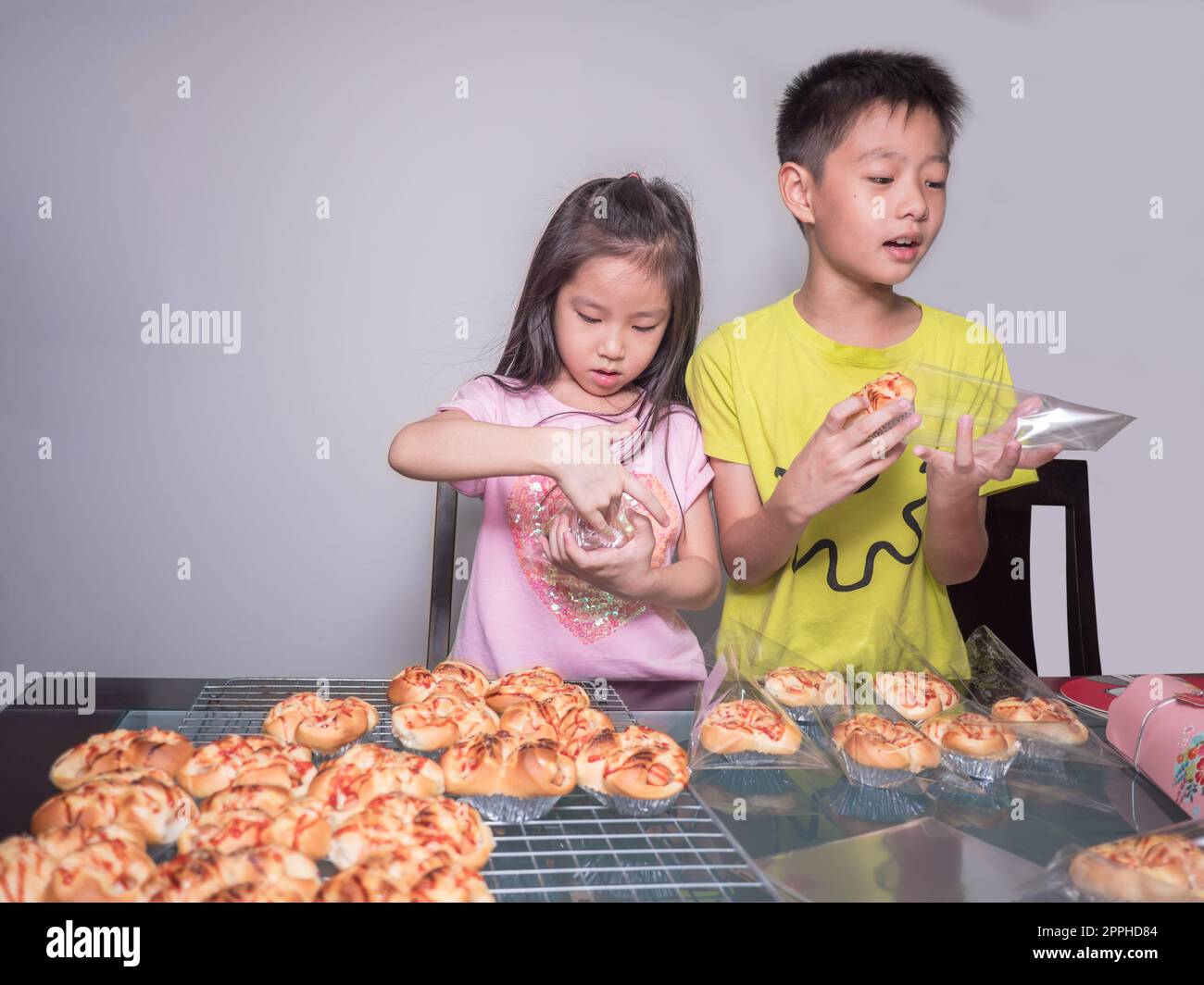 Adorable kid girl and boy separate packing baked pork sausage with ...