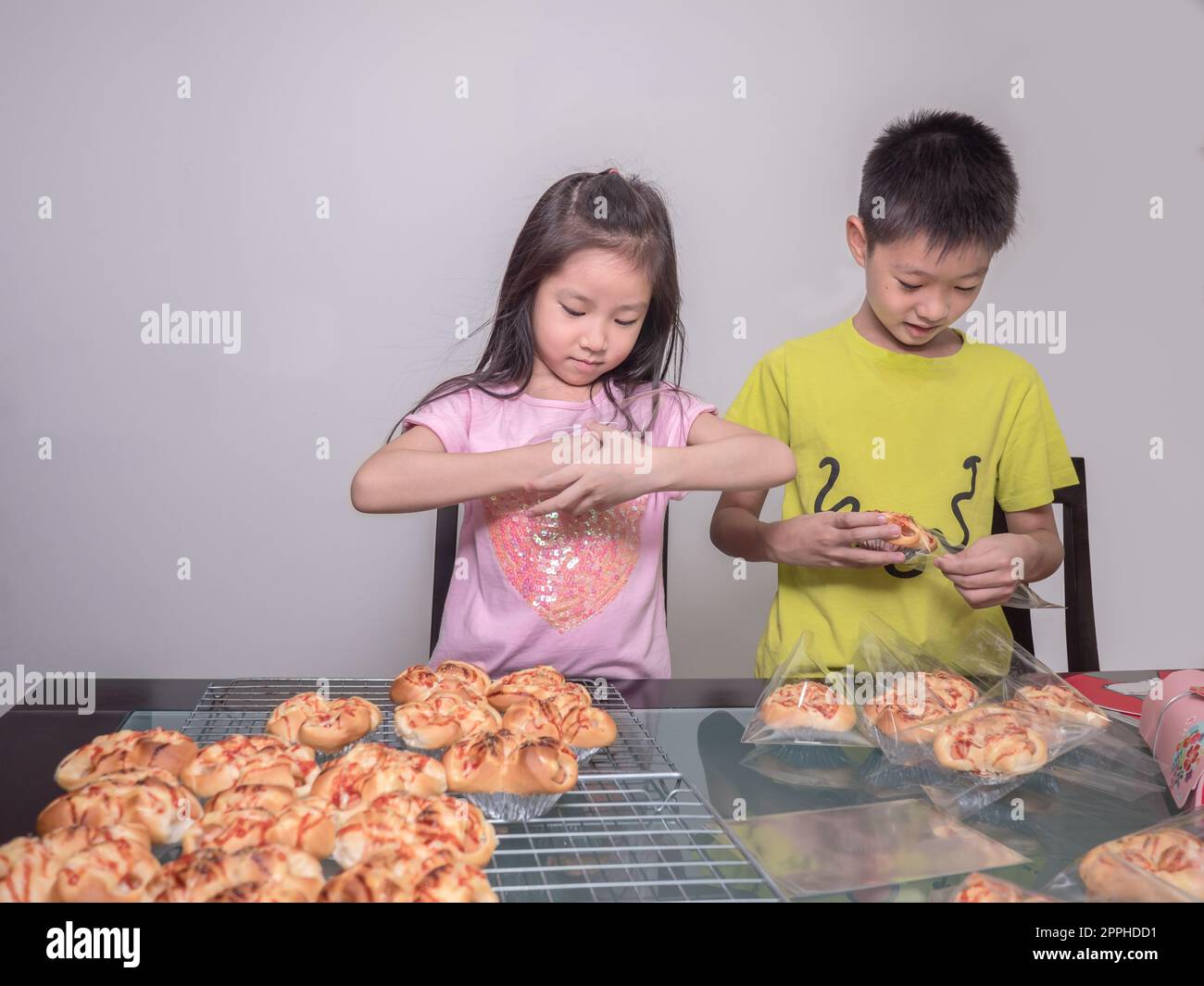 Adorable kid girl and boy separate packing baked pork sausage with ...